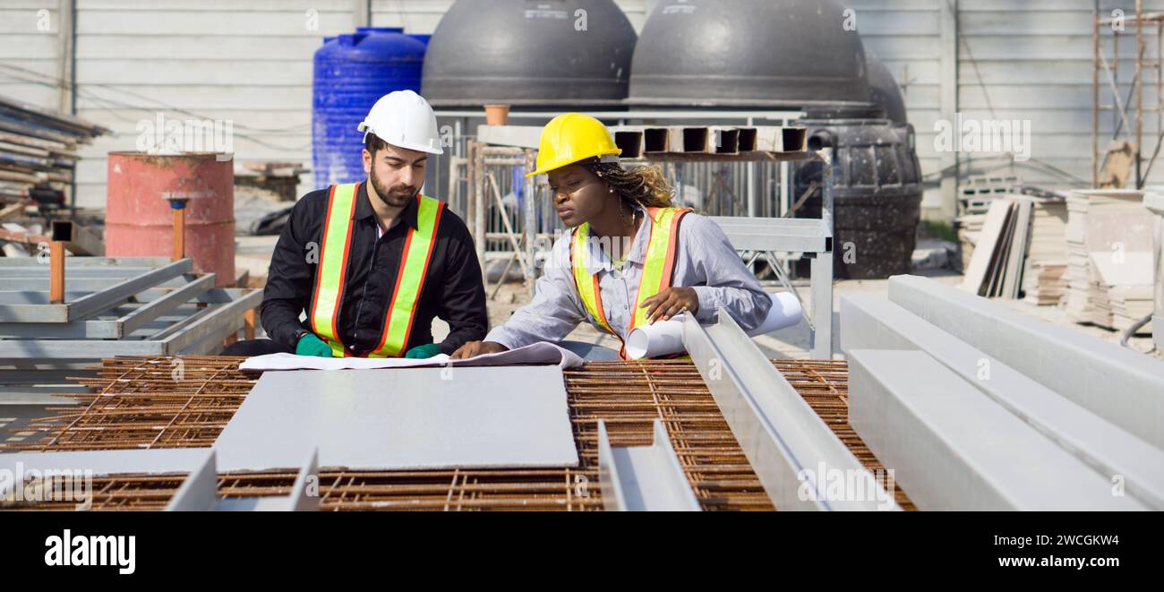 Two construction workers are working on construction tasks in front of ...