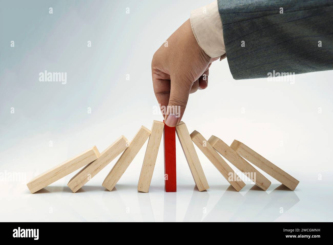 Business hand put a red wooden block into a fallen row of brown wooden ...