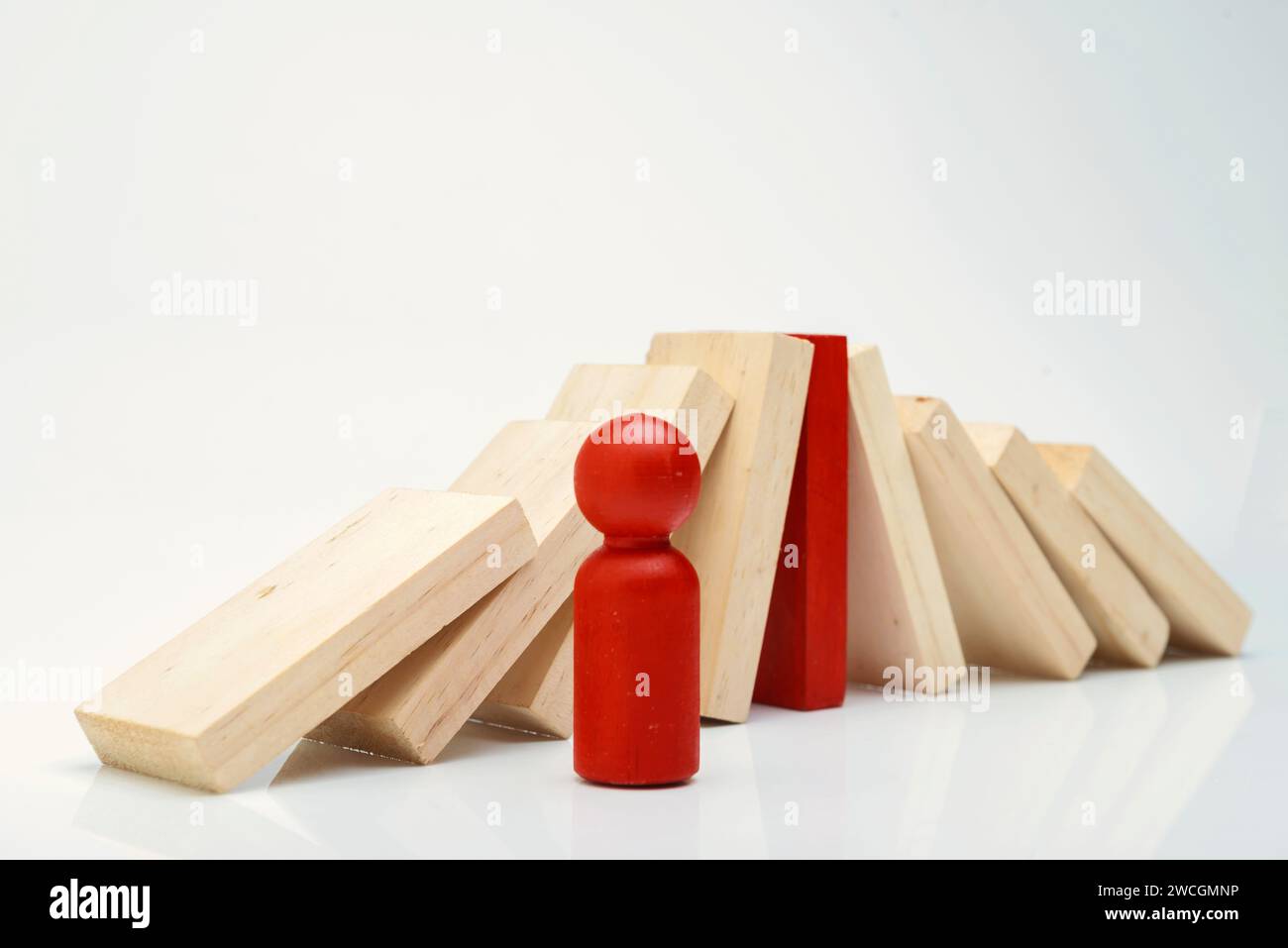 A red wooden figure looking at a red wooden block hold on a fallen row ...
