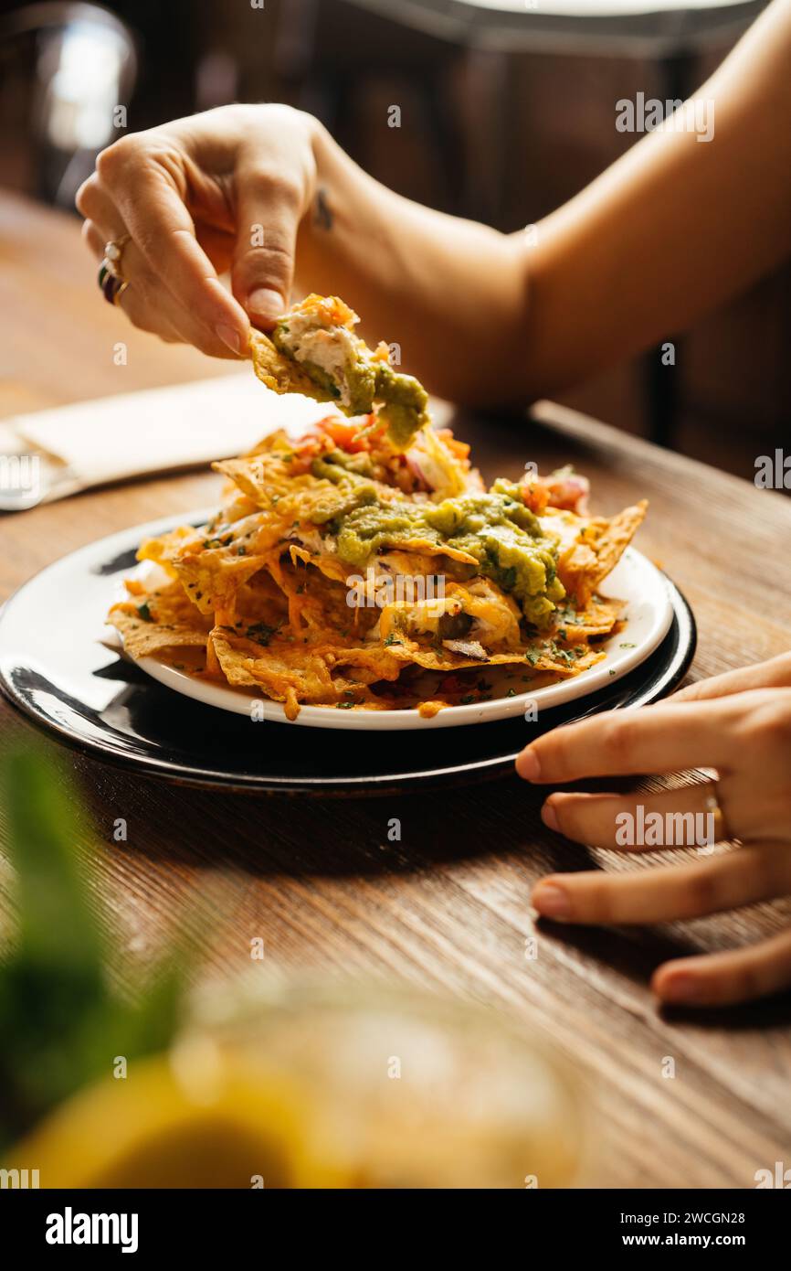 Crop client eating yummy nachos in restaurant Stock Photo - Alamy