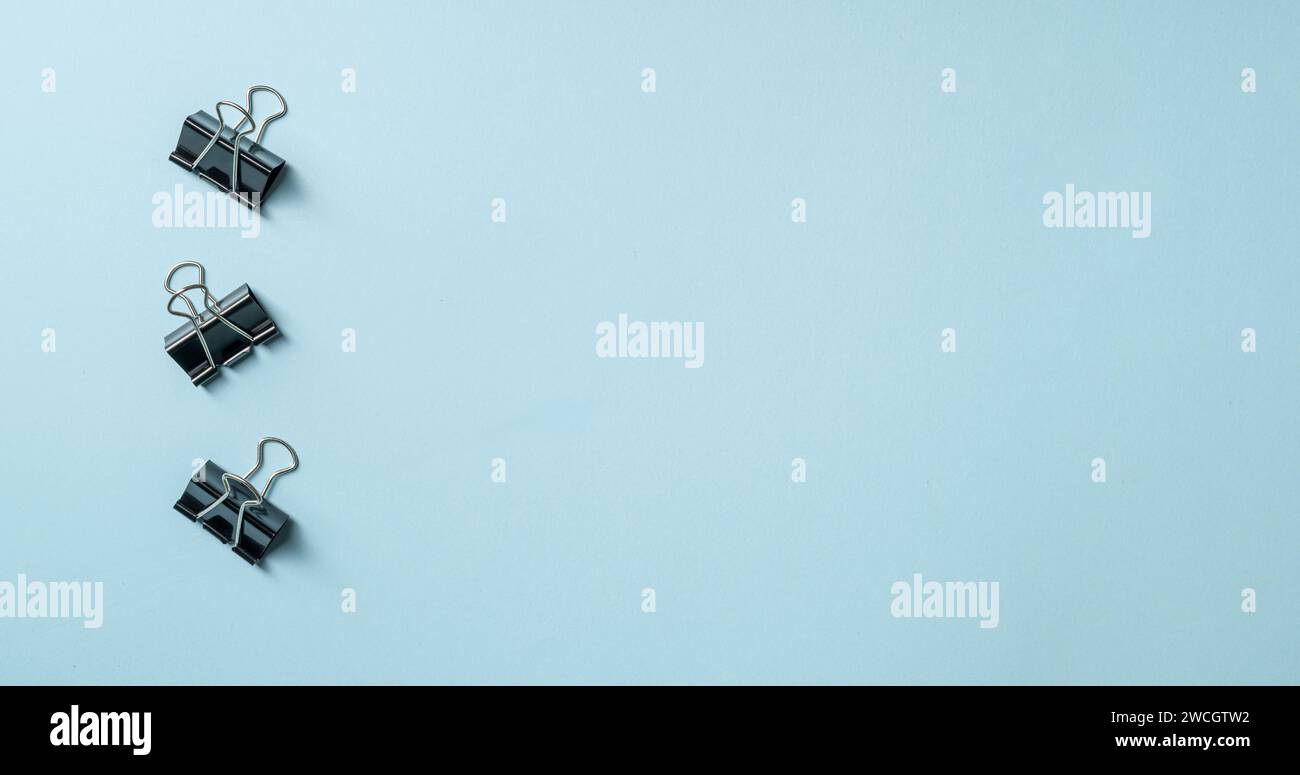 Top view of three black binder paper clips on blue background Stock ...