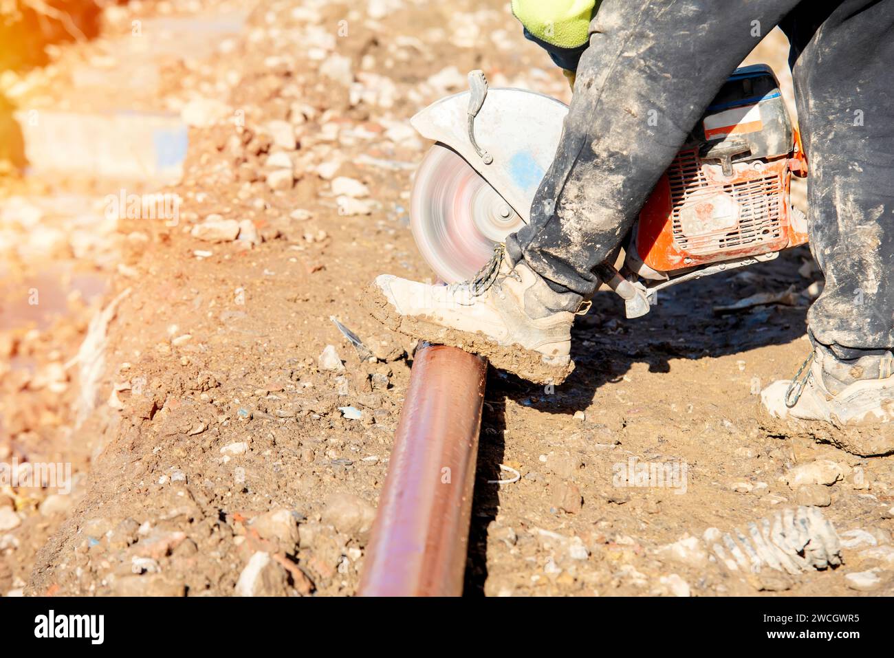 Builder cutting plastic pipe with petrol concrete saw and a diamond ...