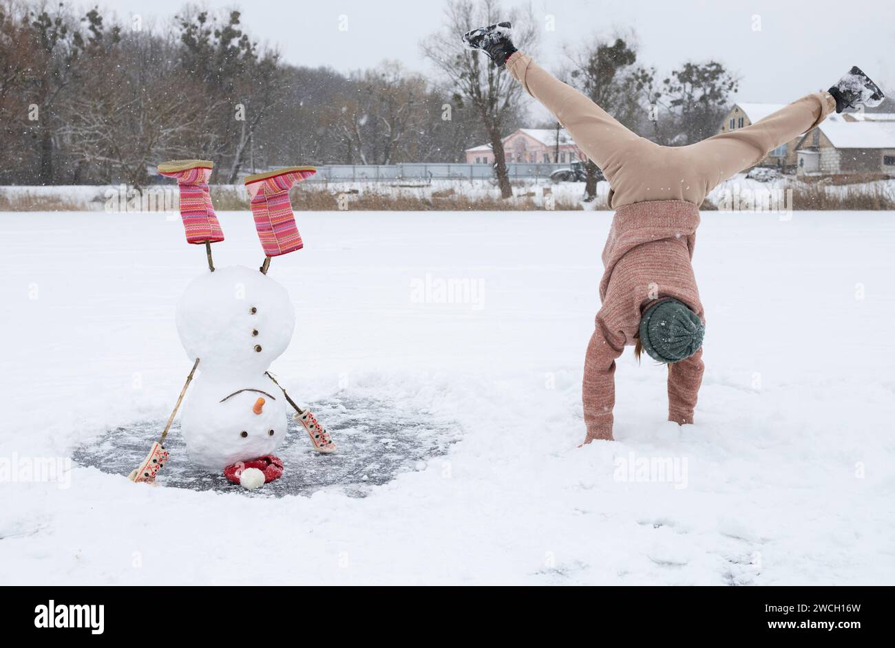 funny snowman stands upside down on a frozen snowy lake. a young ...