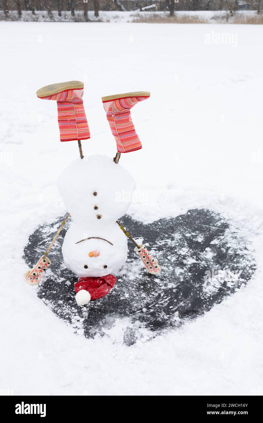 funny snowman in red boots stands upside down on a frozen snowy lake ...