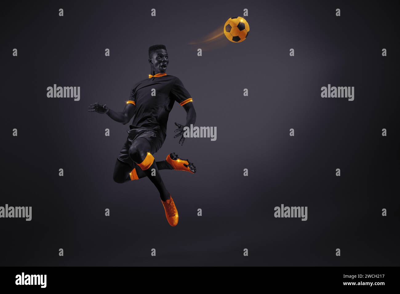 African young man, soccer player in mid-kick with selective orange ...