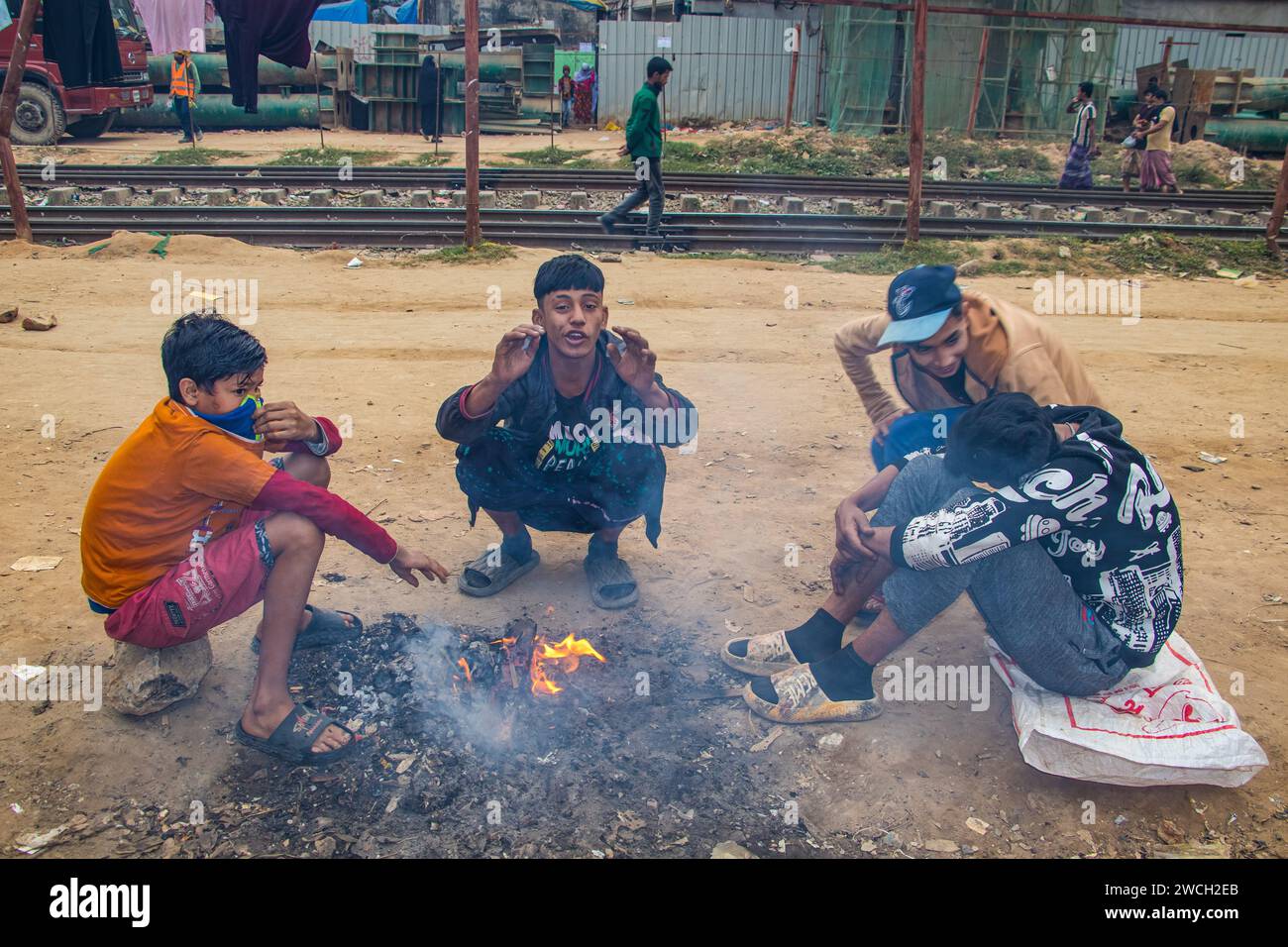Amidst winter's chill, street people gather around a flickering fire ...