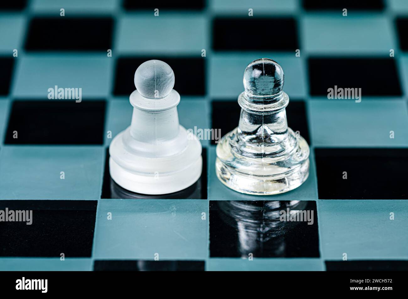 two opponent glass chess pawns on a glass chess board, black background ...