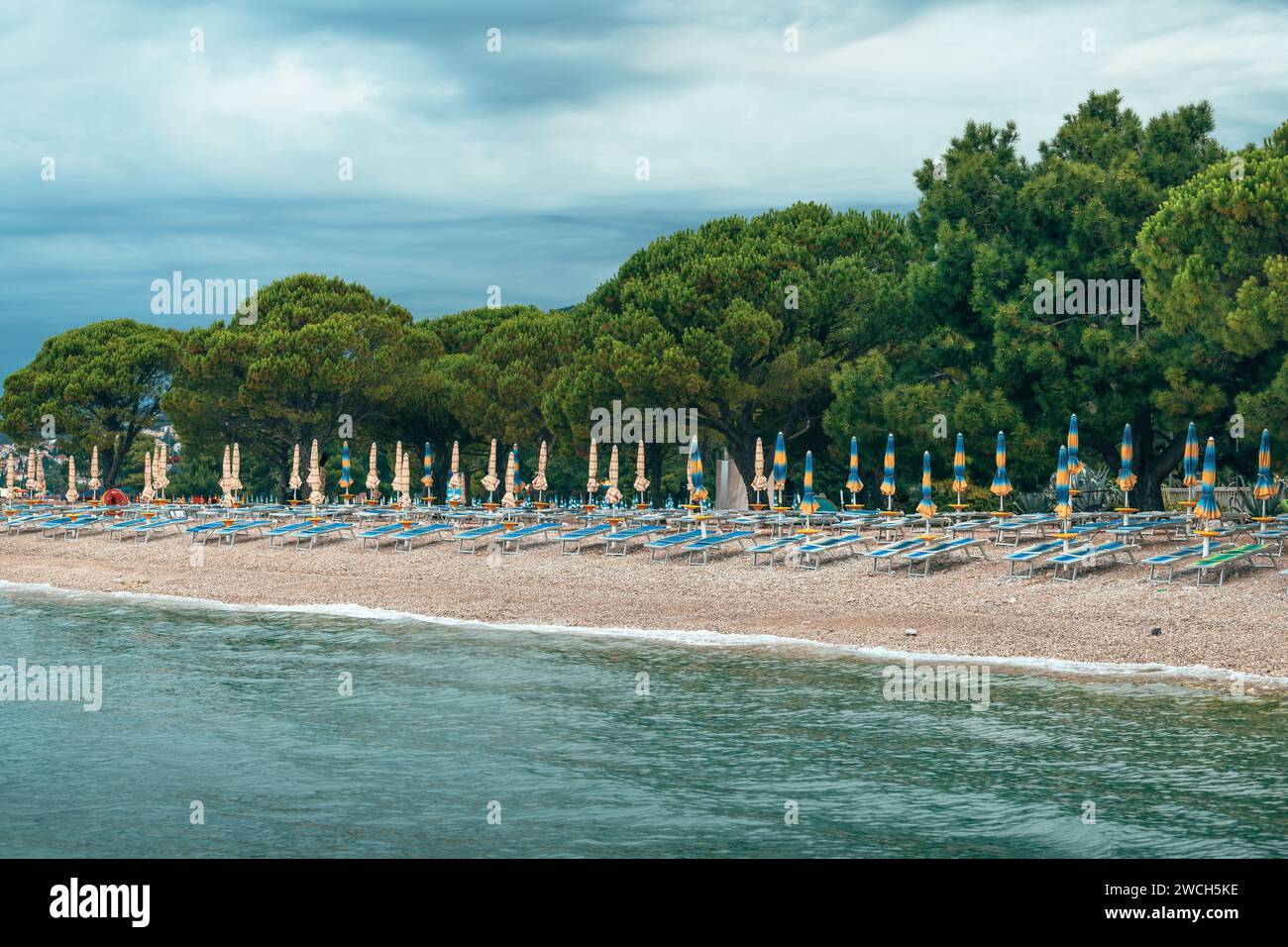 Folded beach umbrellas and empty deck chairs on town beach in ...