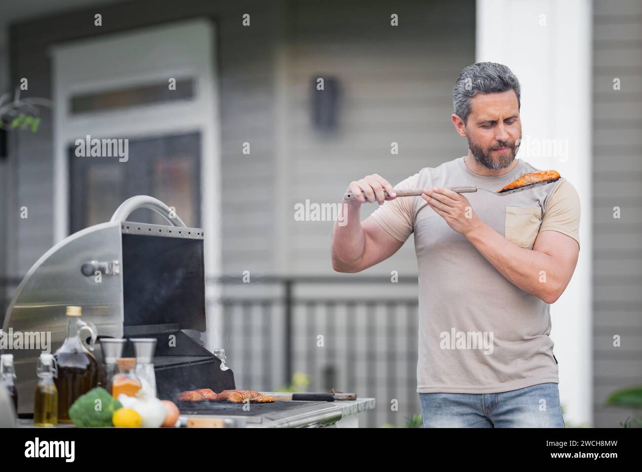 Handsome smiling hispanic man making barbecue at backyard. Picnic ...