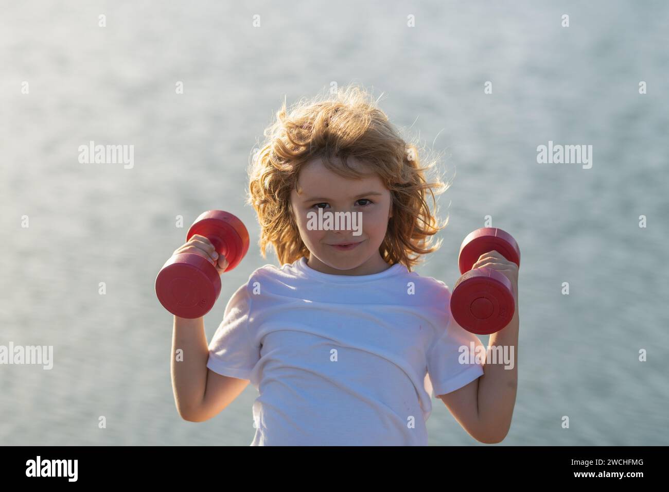 Cute child boy pumping up arm muscles with dumbbell. Fitness kids with dumbbells Stock Photo - Alamy