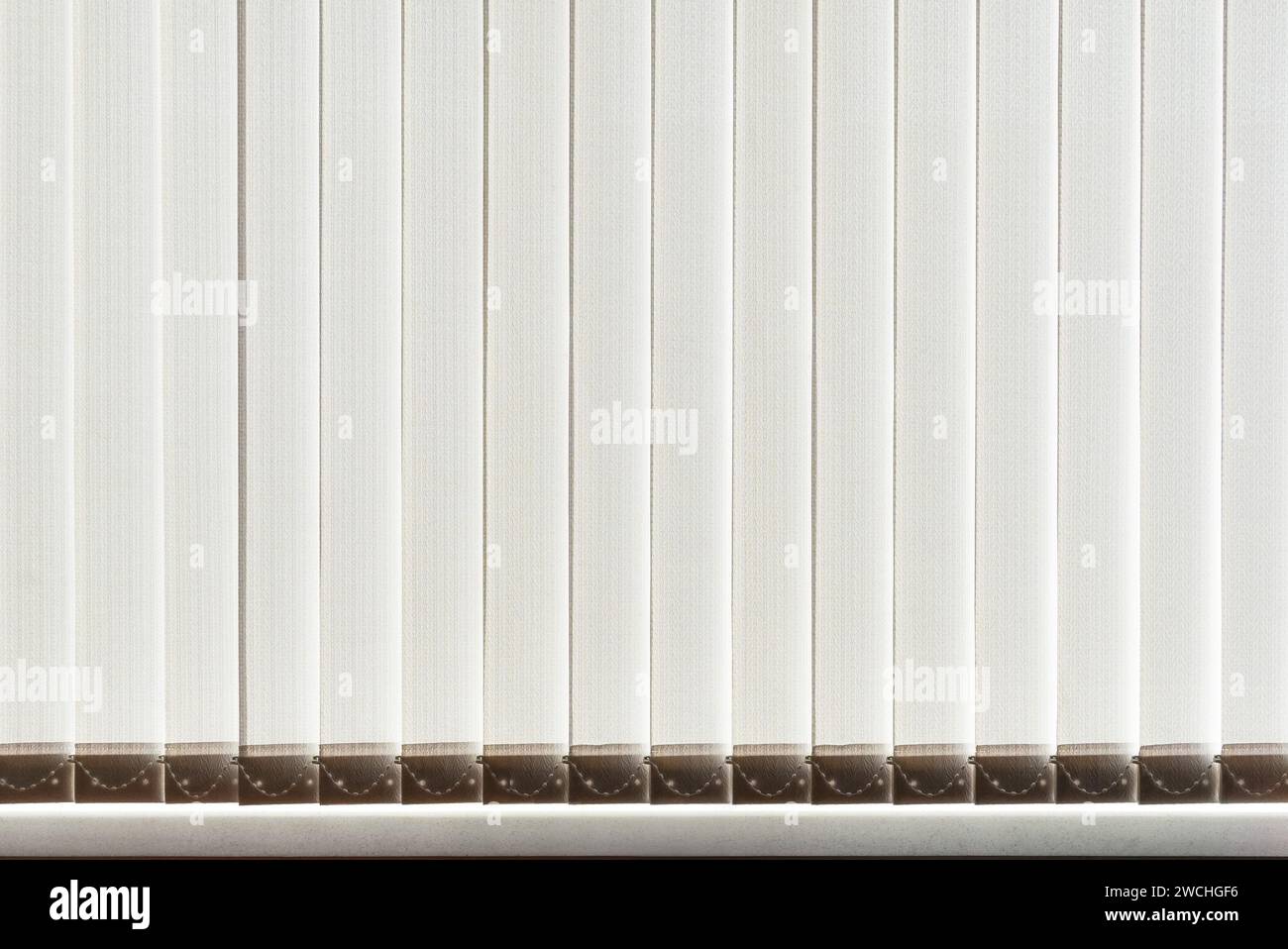 Vertical fabric blinds on the window backlit by sunlight. Background ...