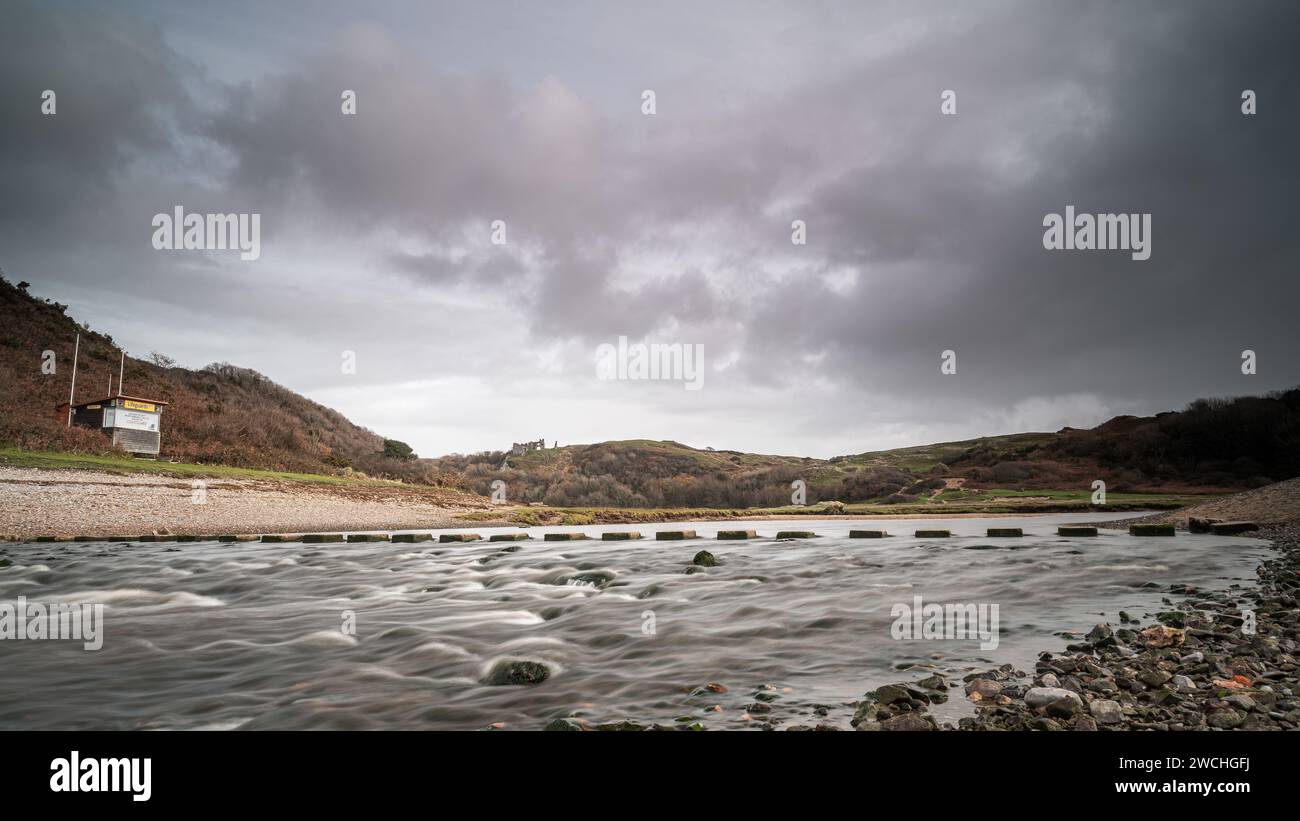 Stepping stones, crossing a river, with Pennard Castle, in the ...