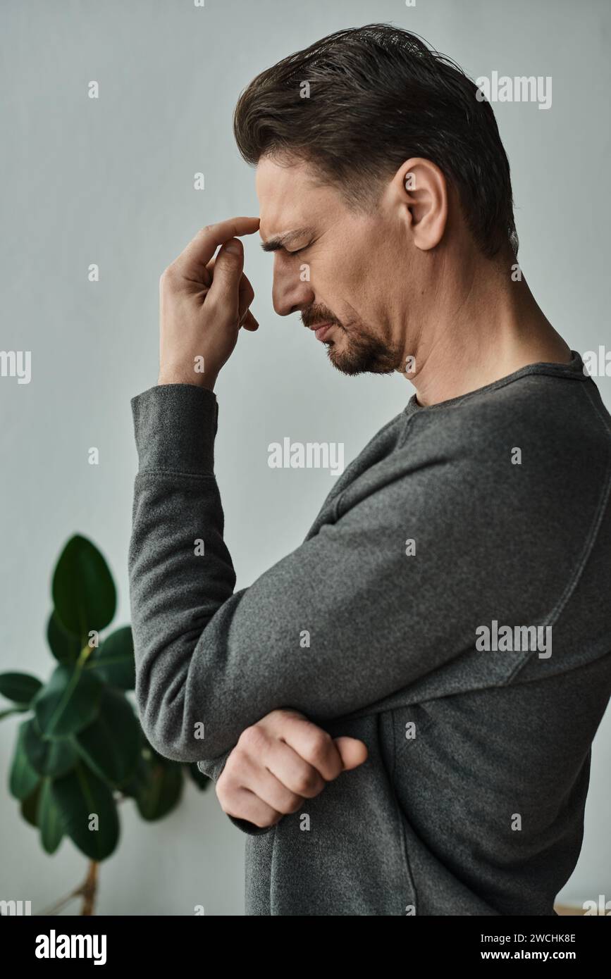 stressed and bearded man with closed eyes frowning while suffering from ...