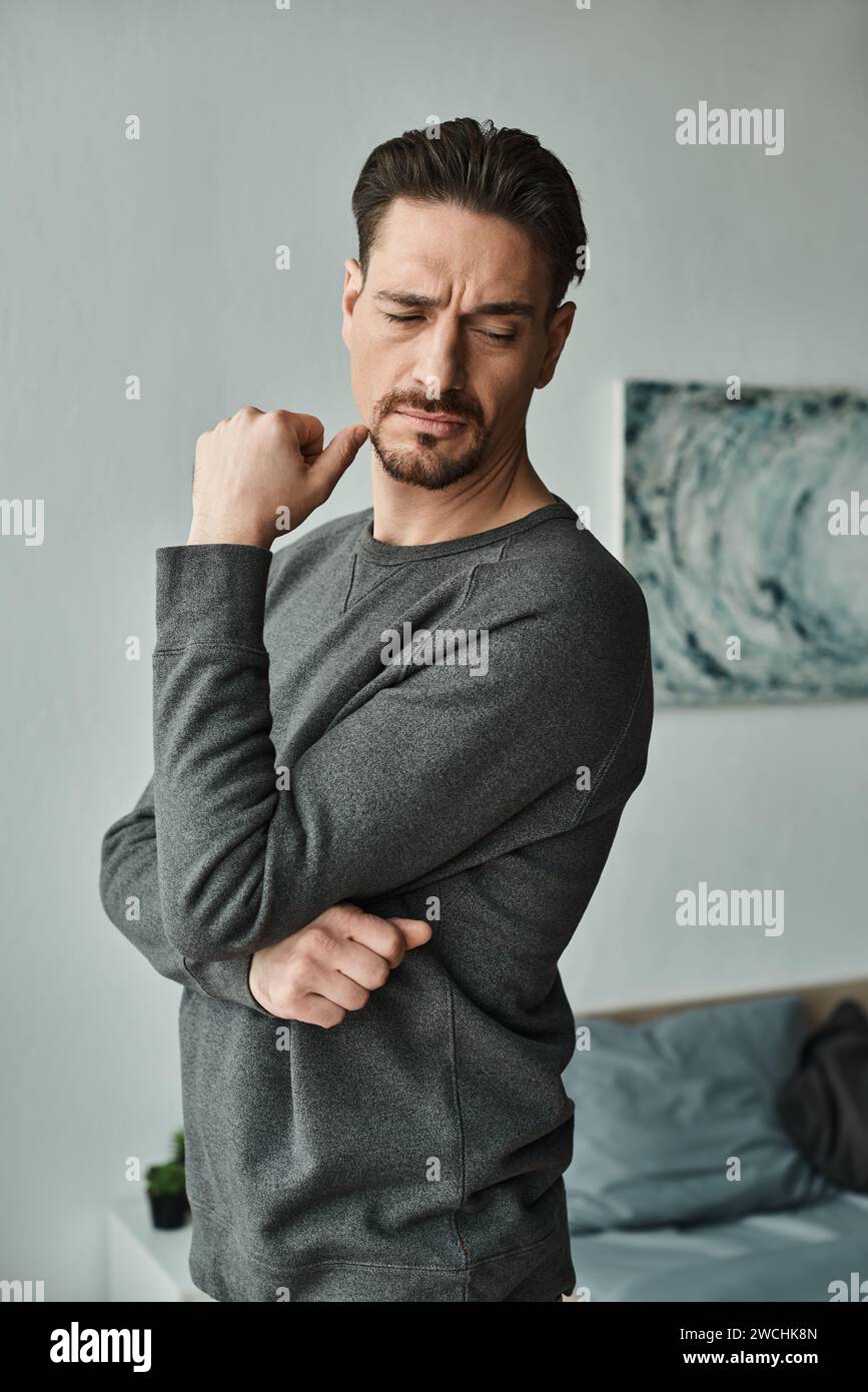 bearded man feeling discomfort and ache while standing at home, muscle ...