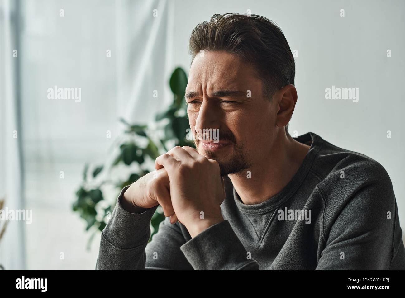 upset bearded man in casual home wear feeling unwell and frowning while ...