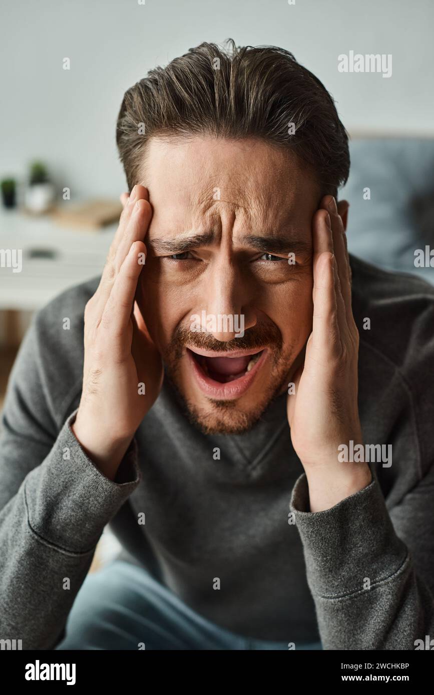 bearded man feeling sharp pain and frowning while screaming and looking ...