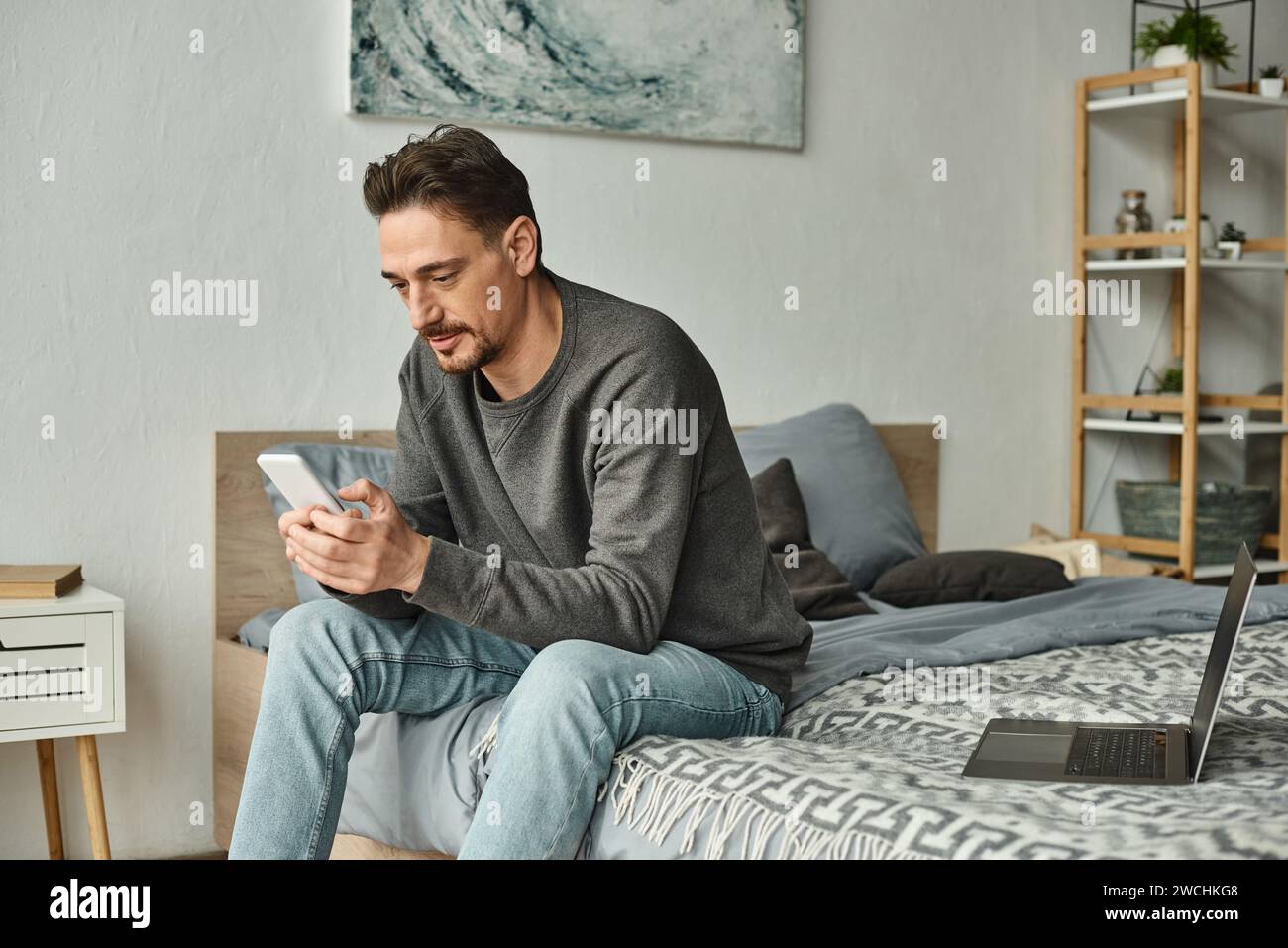 bearded man texting on mobile phone while working remotely from home ...