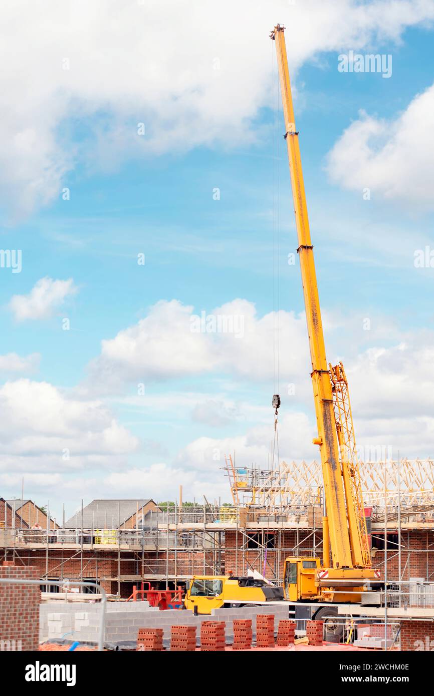 Mobile crane at building site lifting joist for new house roof ...