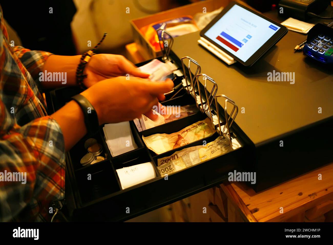 Cashier counting the money for change on desk when customer paying for ...