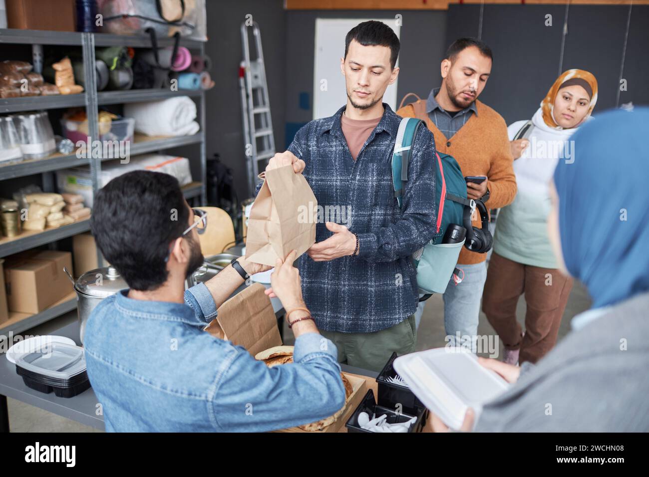 Group of Middle Eastern people standing in line at refugee help center ...