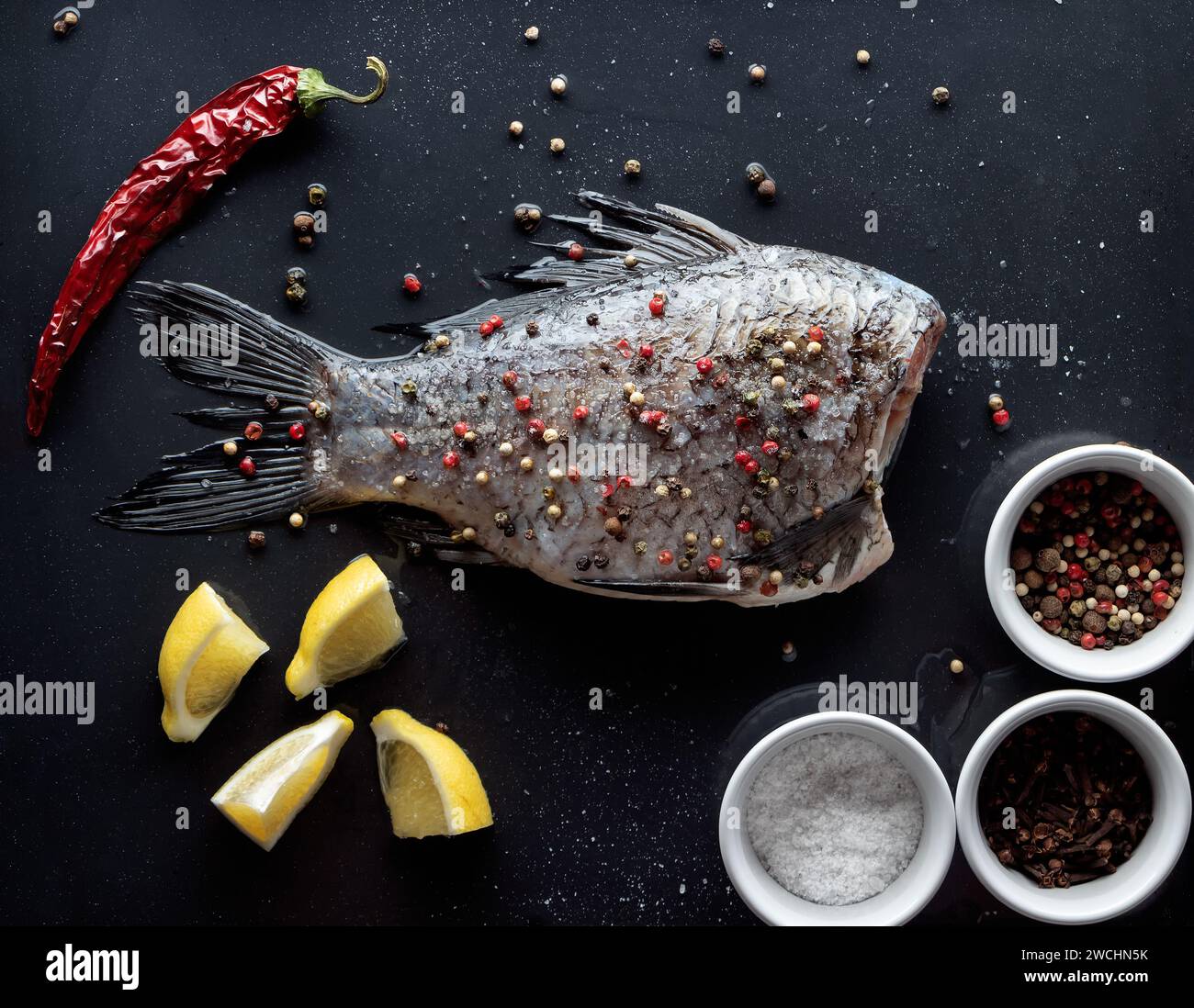 Fresh fish sprinkled with pepper and spices ready to bake Stock Photo ...