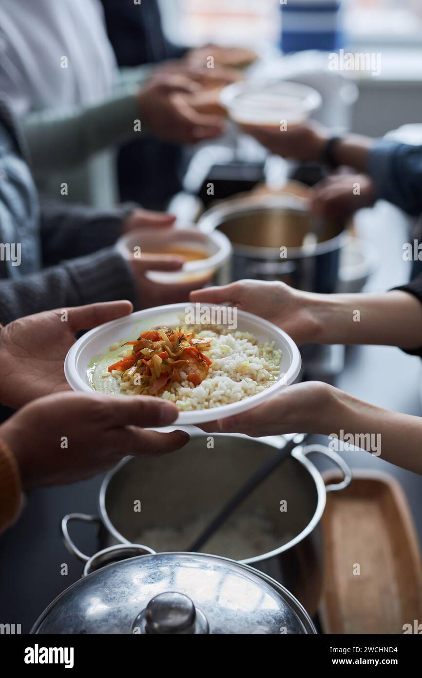 Vertical closeup of volunteers helping at soup kitchen and giving out ...
