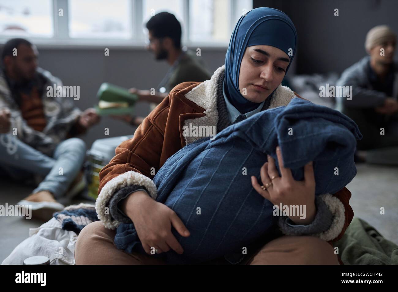 Portrait of distressed young Middle Eastern woman holding baby while ...