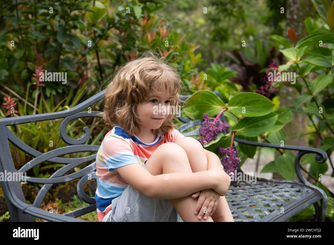 Kid sit on bench. Lifestyle portrait of cute kid outdoors. Summer kids ...