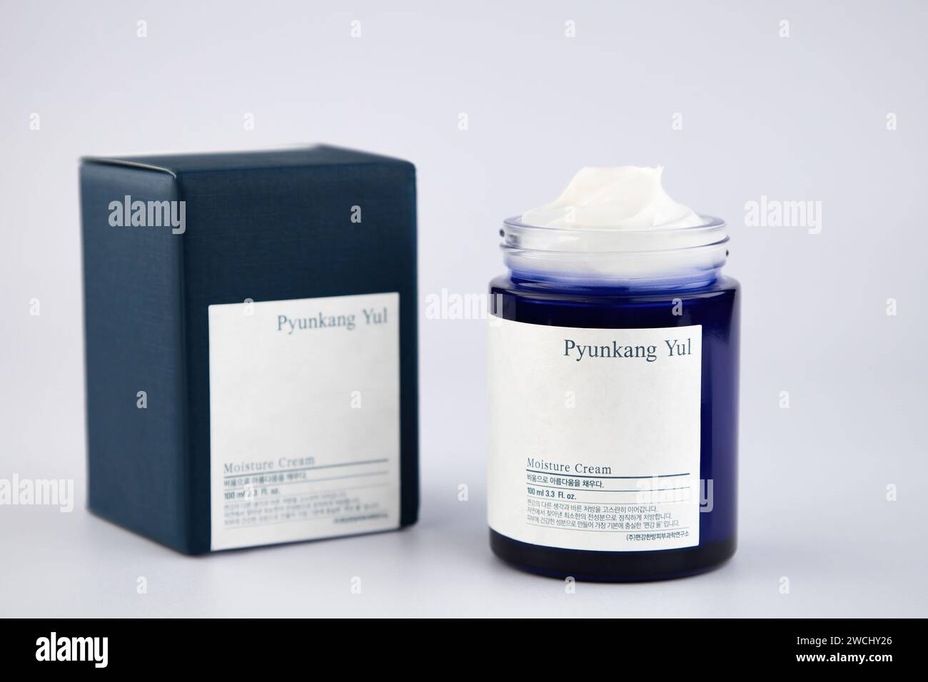 An open glass bottle of Pyunkang Yul brand face moisturizer next to the ...