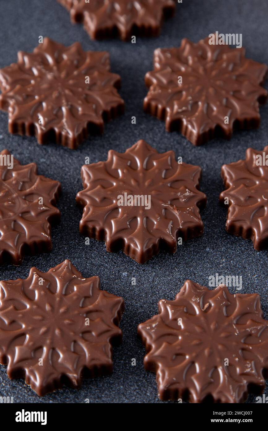 Chocolate candies in the shape of snowflakes. Brown food background ...