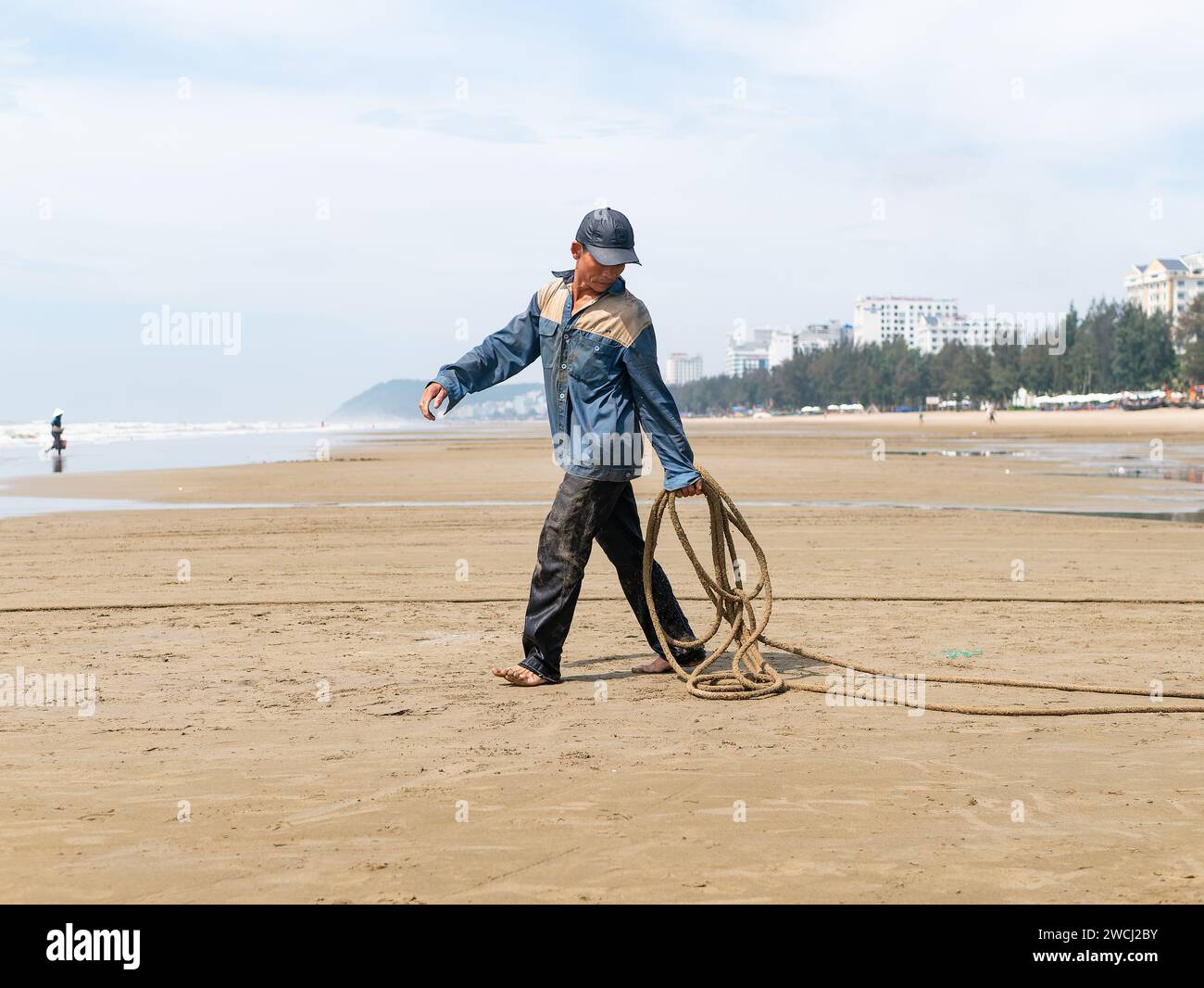 Fisherman hauling a rope to retrieve his boat at Sam Son Beach, Thanh ...
