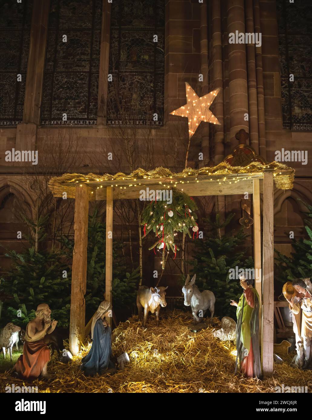 An intricately detailed nativity scene is illuminated by a warm glow ...
