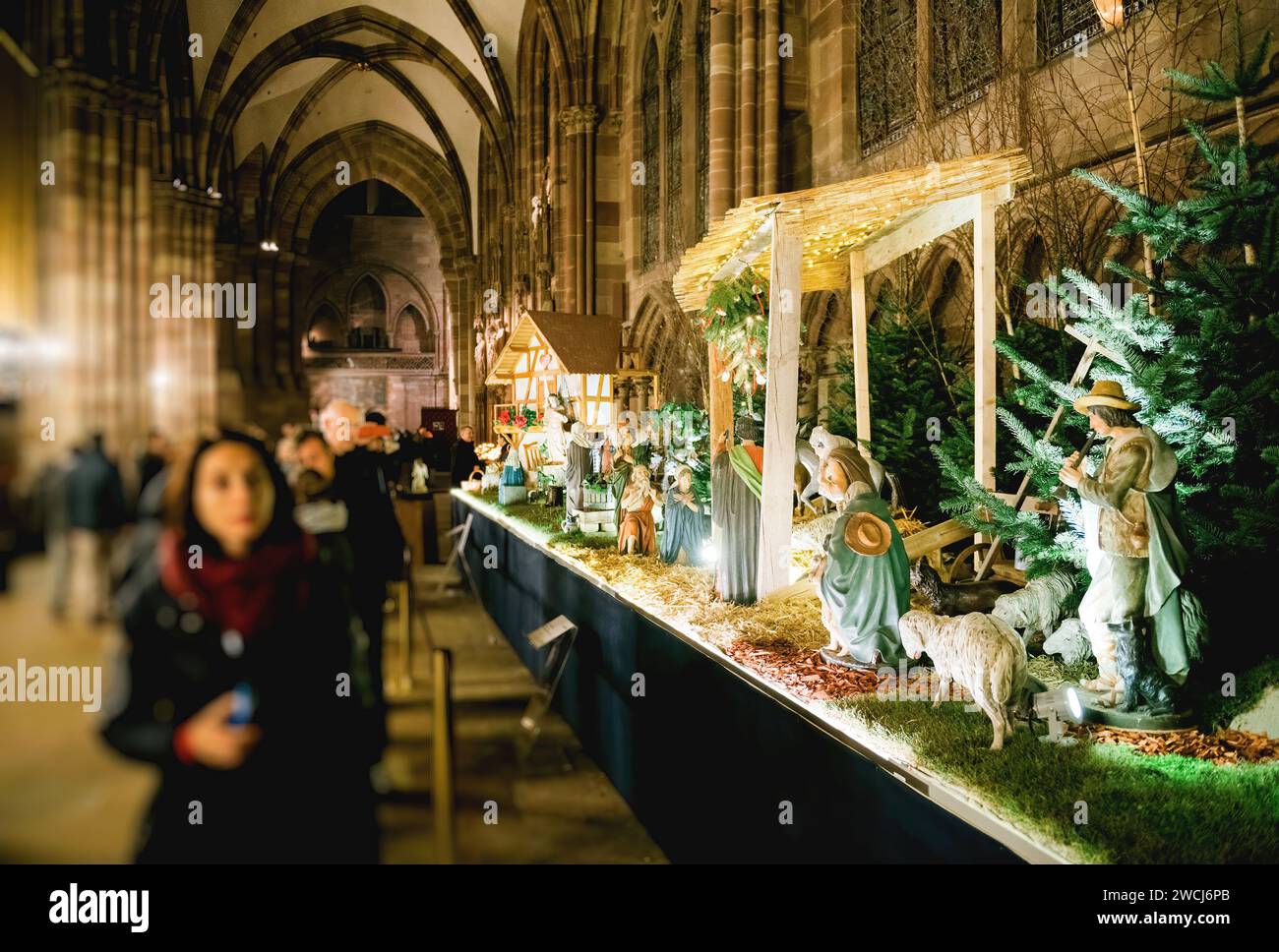 Defocused view of spectators admire a detailed manger scene depicting ...