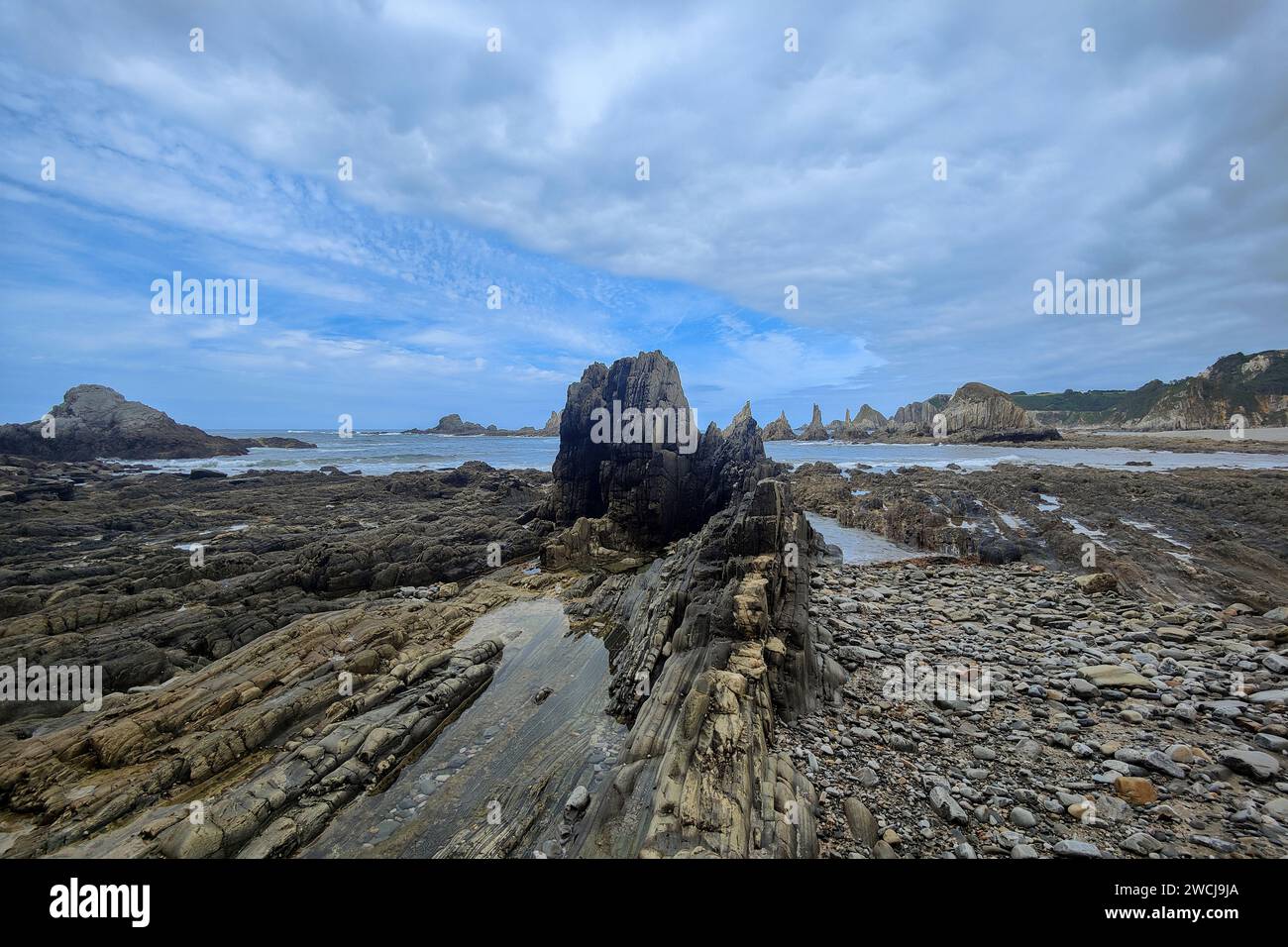 serene yet rugged shoreline with jagged rock formations and pools of ...