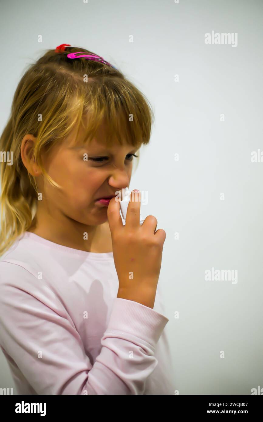 little embittered girl in pajamas sprays her nose with anti-pneumonia ...