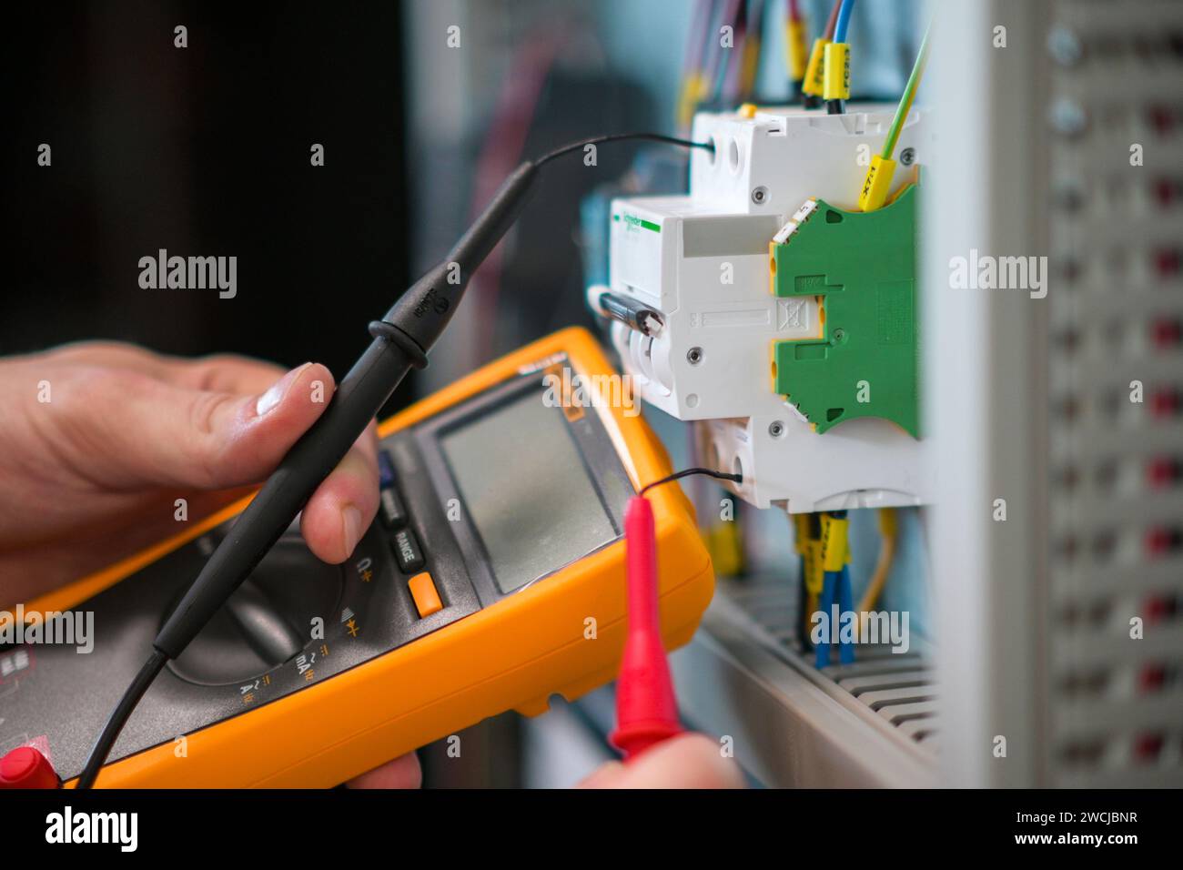 an electrician working in an electrical cabinet as Tests cables using a ...