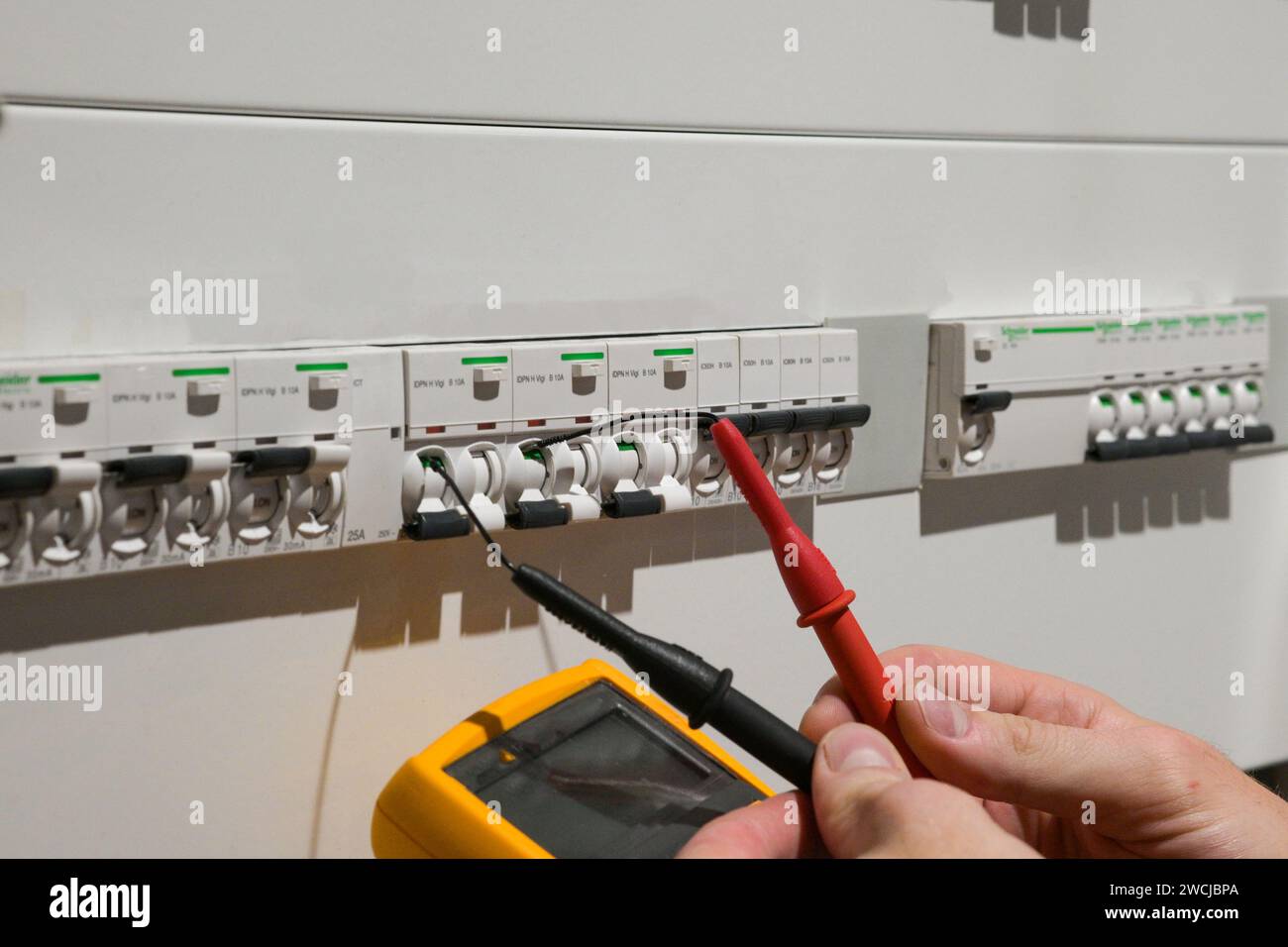 an electrician working in an electrical cabinet as Tests cables using a ...