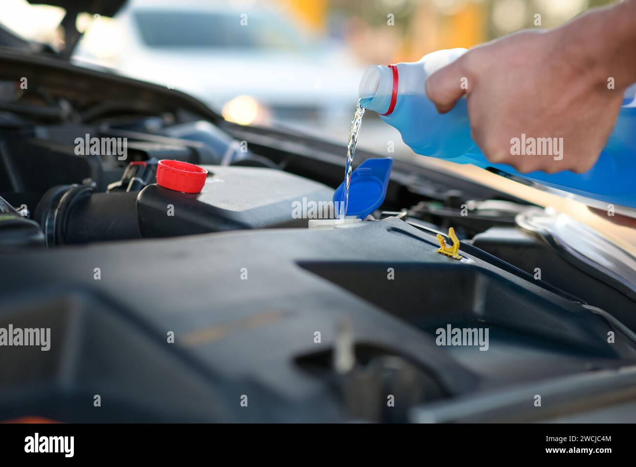 the mechanic adds water to the washers, taking care of the car, close ...