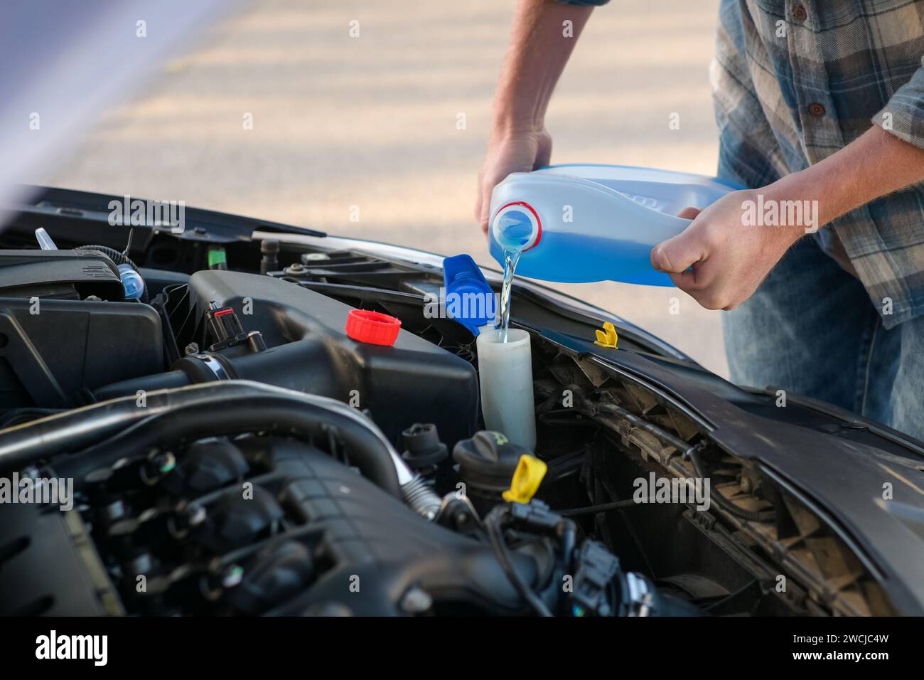 the mechanic adds water to the washers, taking care of the car, close ...