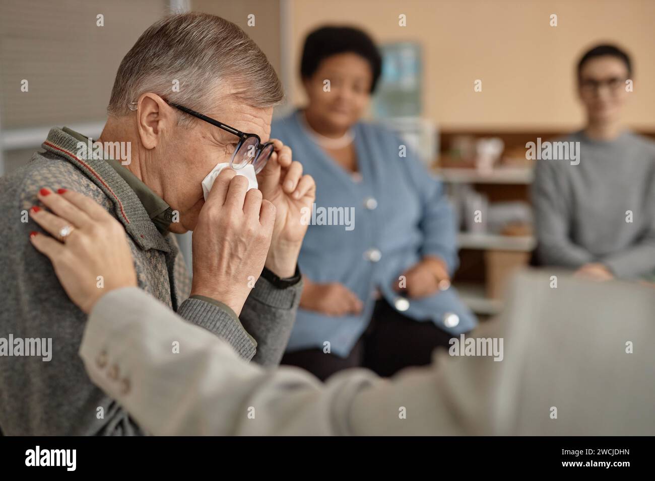 Side view portrait of senior man crying in group therapy session with ...