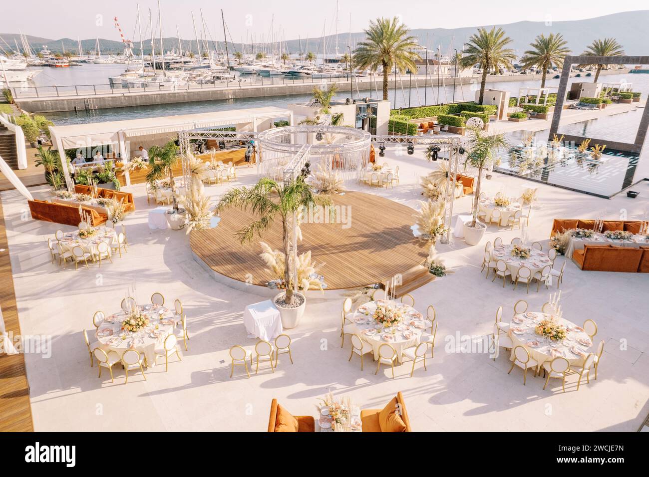 Covered tables stand around a circular stage in front of the pool on a ...