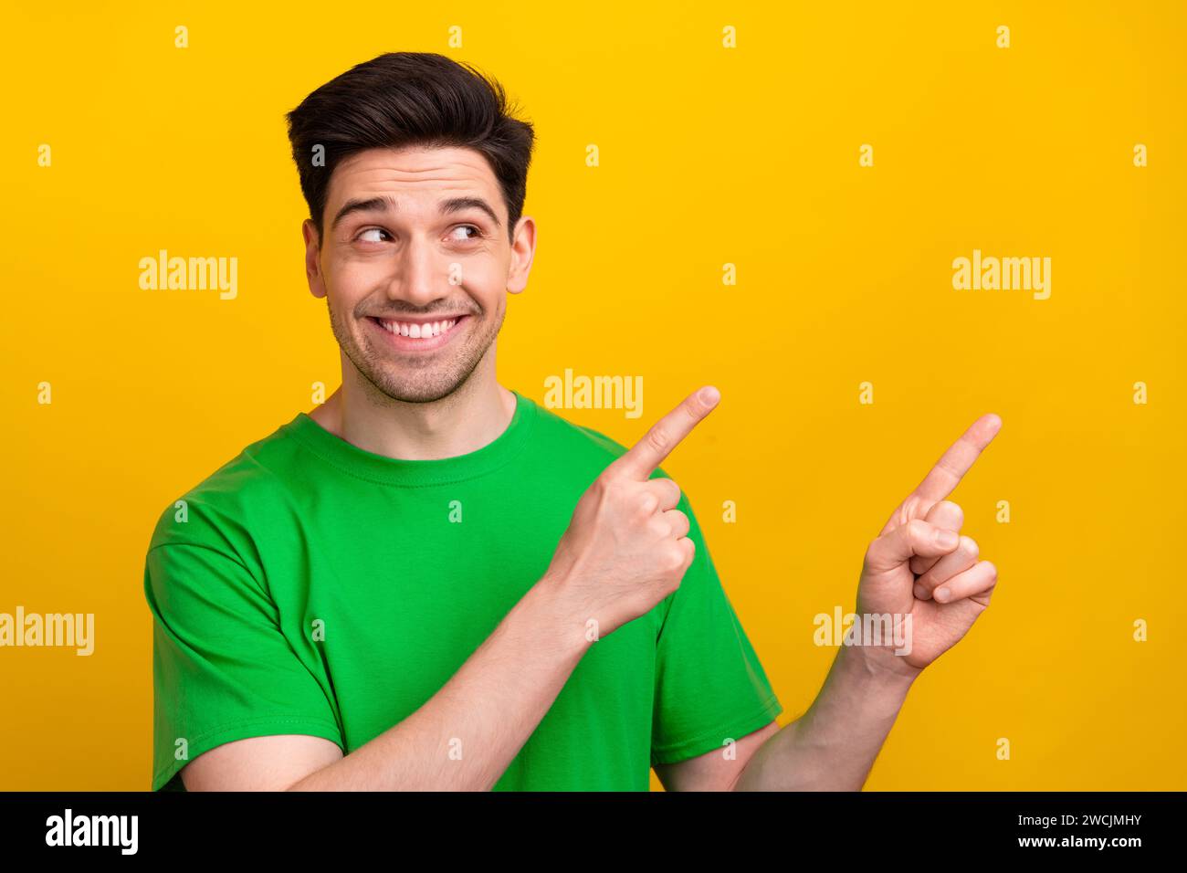 Photo of young happy man in green t shirt direct fingers empty space ...