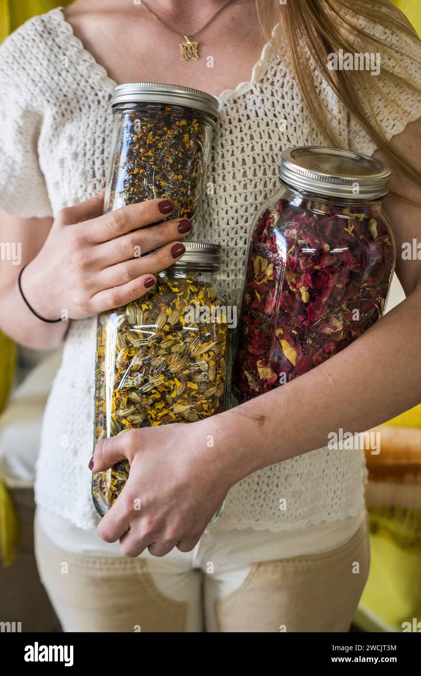 Natural Dye Artist holding jars of saved dried dye stuffs in studio ...