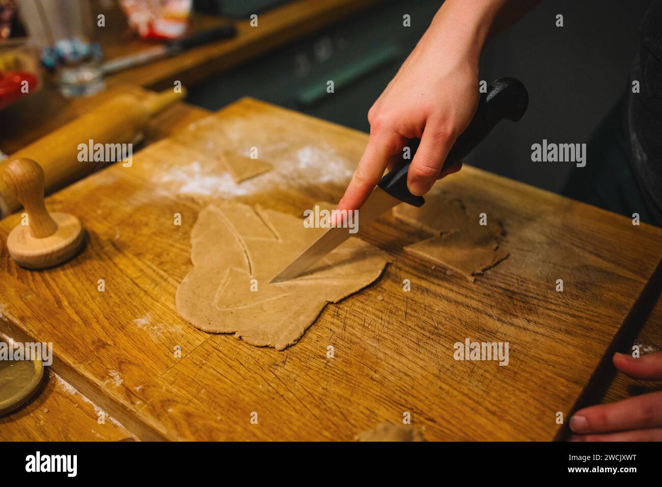 Female hand cut gingerbread dough with a sharp knife at kitchen ...