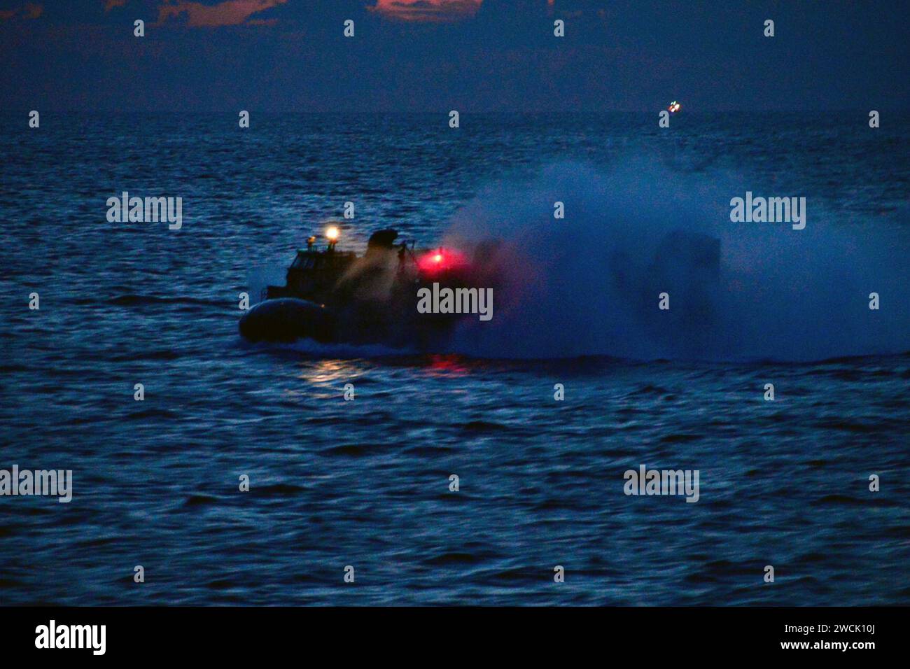 A landing craft, air cushion transits alongside USS Wasp during night ...