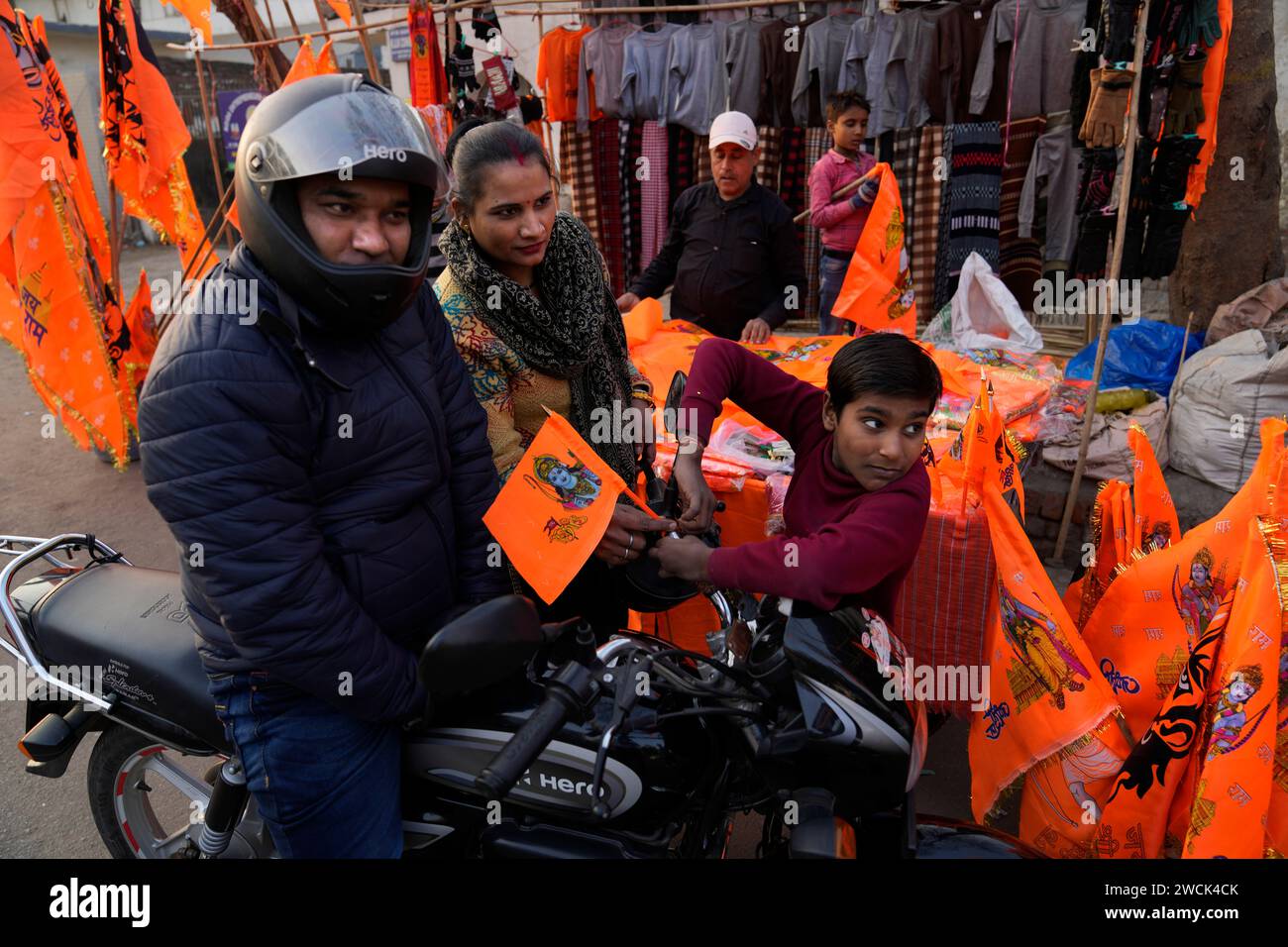 A boy fixes a Hindu Lord Ram's flag on to a motorcycle of a couple on ...