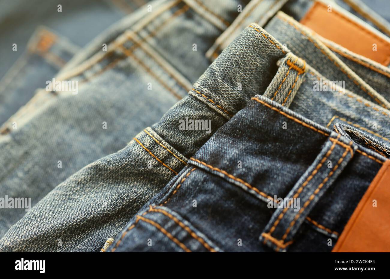 Many jeans in stack in wardrobe room. Row of pants denim jeans in ...