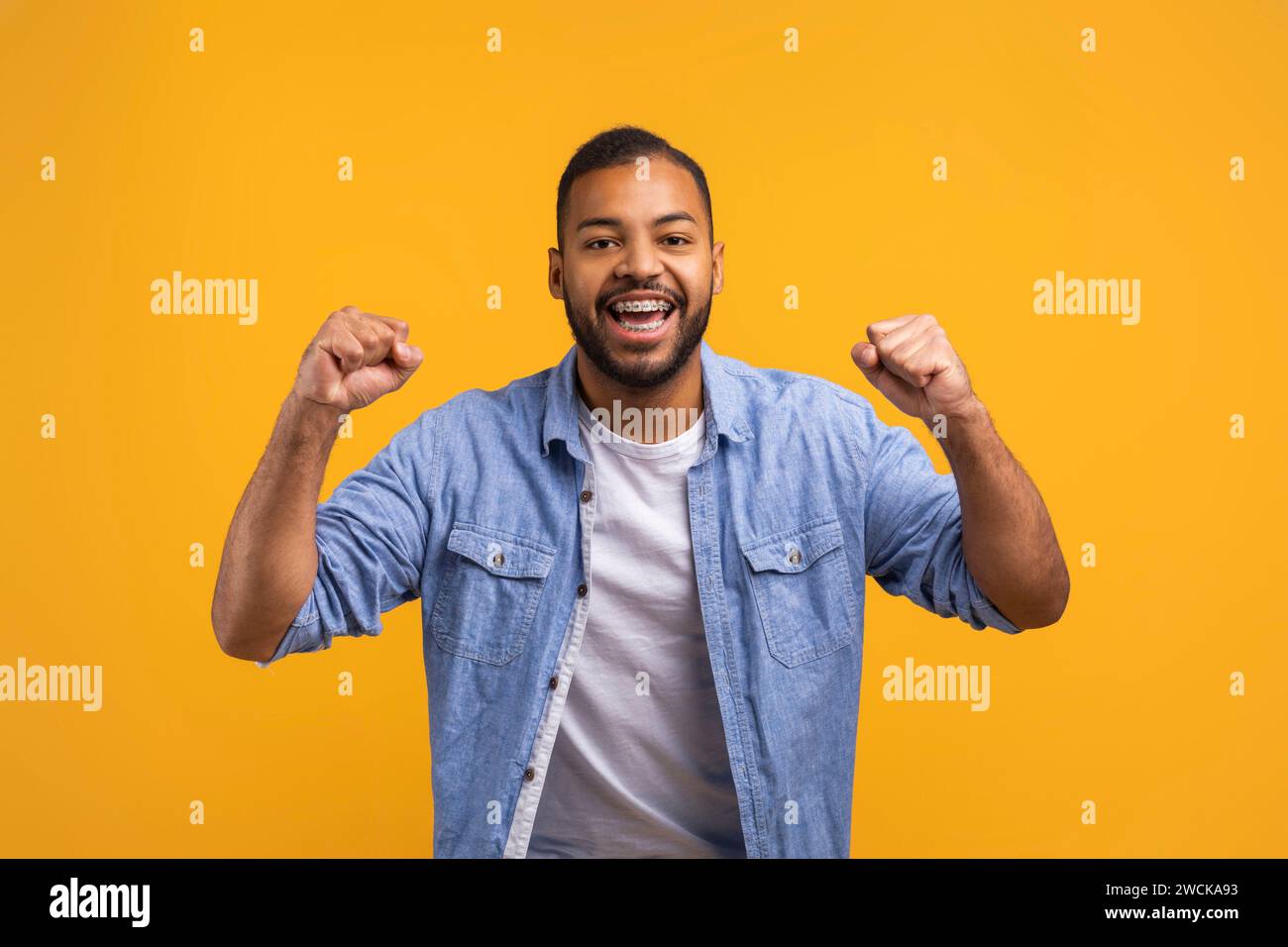 Joyful young black man celebrating success on yellow studio background ...