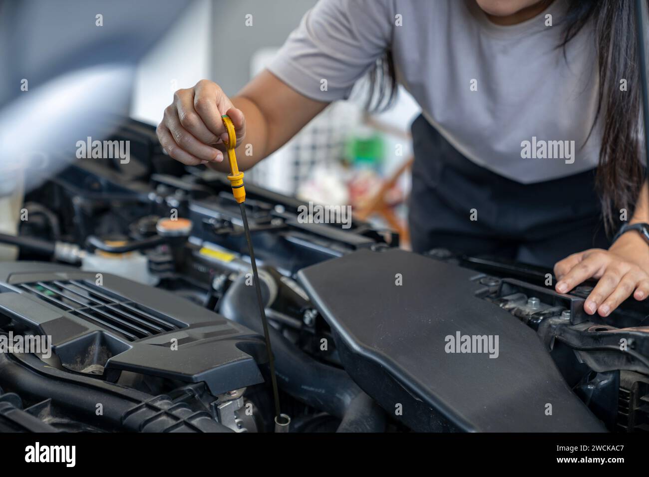 A young woman checking the car engine oil by herself Stock Photo - Alamy
