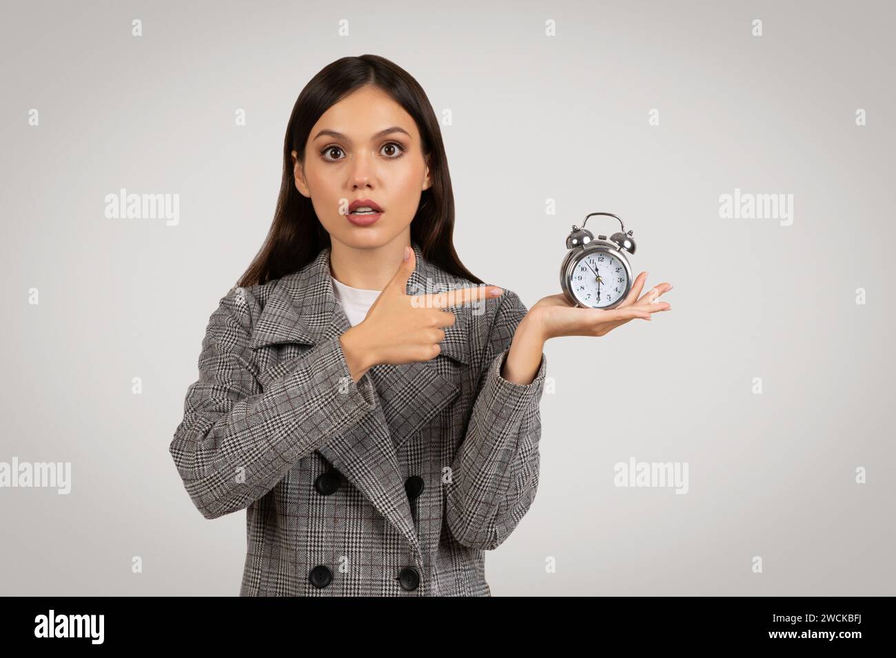 Businesswoman with clock, emphasizing time management Stock Photo - Alamy